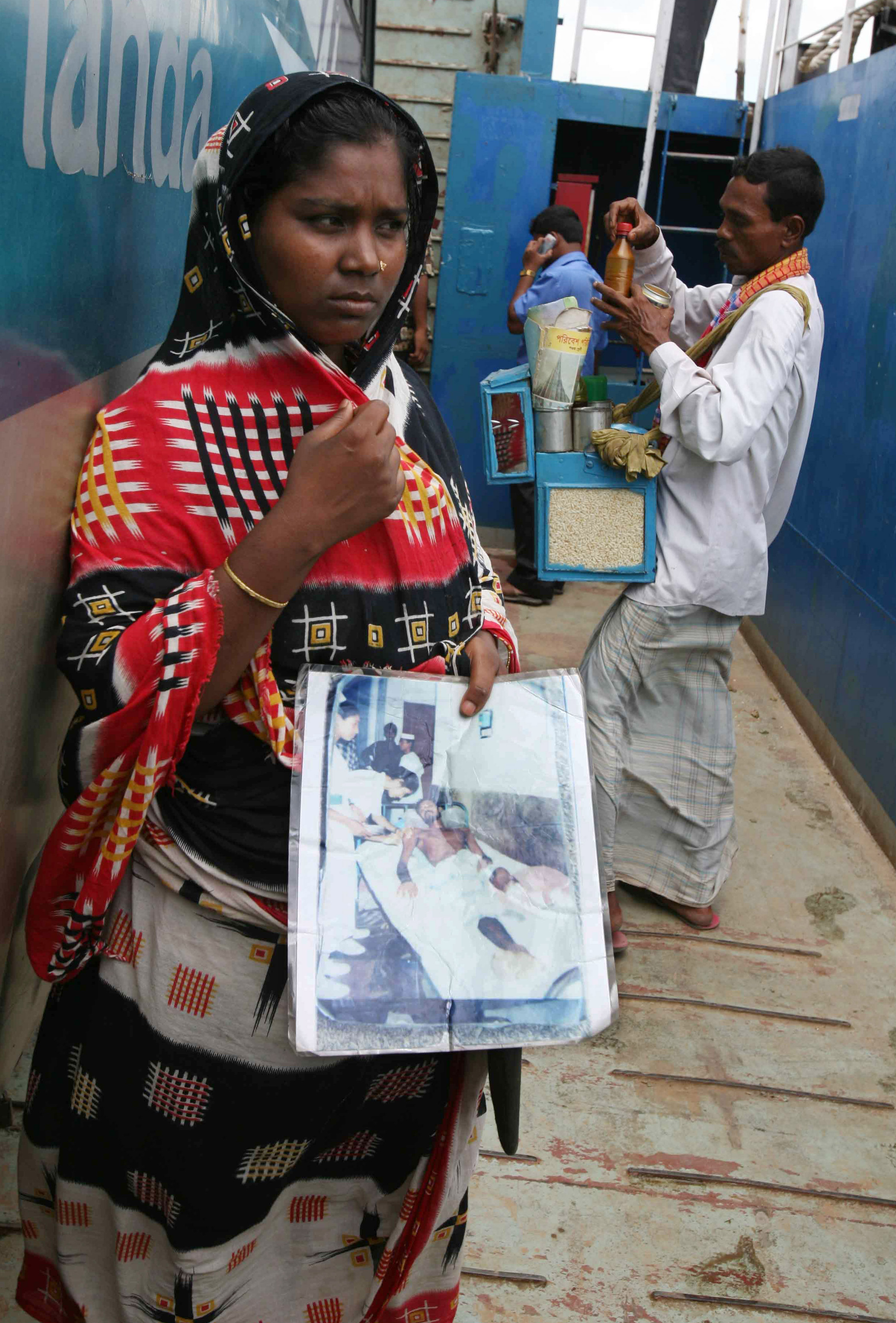 A woman holds a picture of a sick relative and asks for help in one of ...