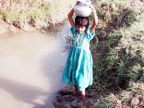 A girl fetching water from a stream. | The New Humanitarian