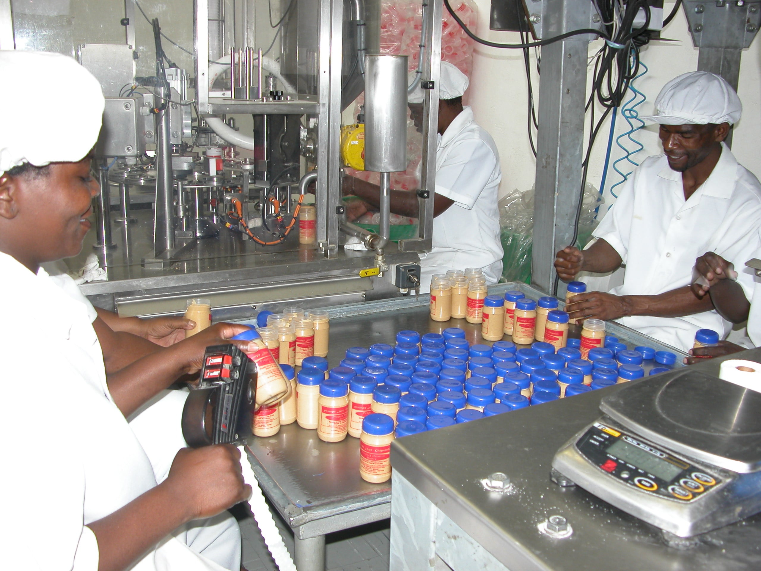 Workers at the Project Peanut Butter factory label containers of Plumpy ...