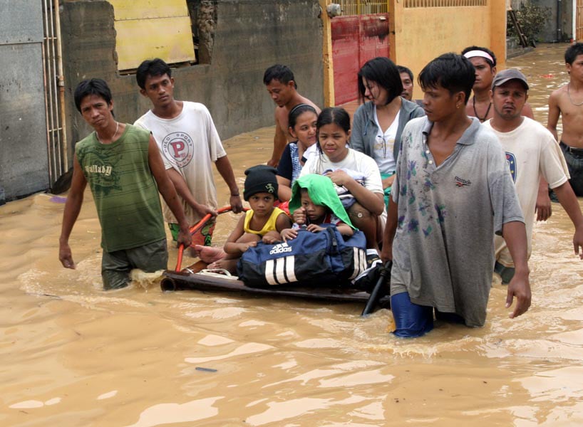 Residents use a makeshift raft to relocate children in this flooded ...