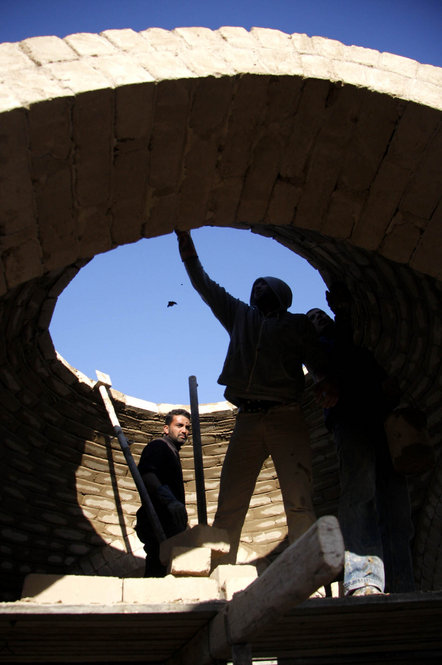 Palestinian workers build a house with mud bricks in Jabaliya town ...