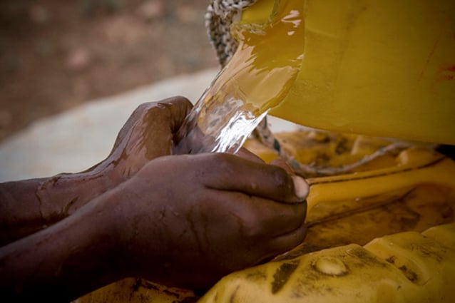 Fresh water being poured into a jerrycan. Harshin district, in the ...