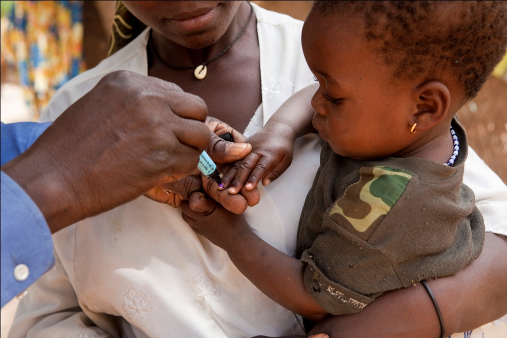In Chad, health worker marking a child's finger to show she has ...
